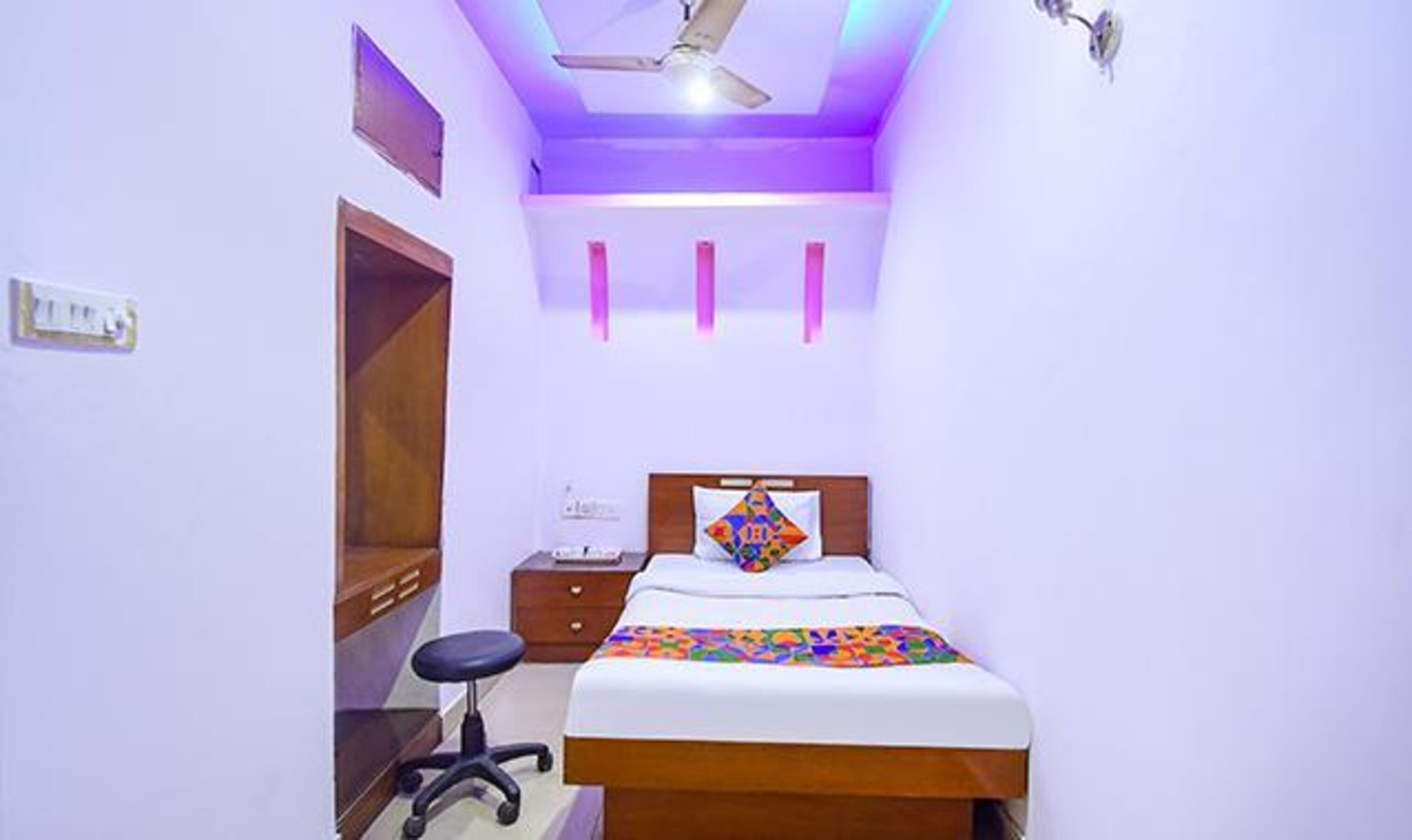 Quarto com cama, escrivaninha, cadeira e ventilador de teto.