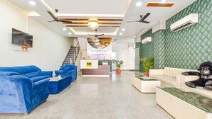 Um lobby de hotel moderno com balcão de recepção, área de estar e escadaria.