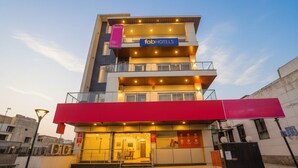 Um hotel de vários andares com um toldo vermelho chamativo, uma placa 'fabHOTELS' e uma placa 'fretels' sobre a entrada.