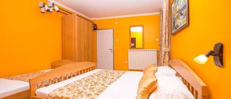 Quarto com duas camas de madeira, uma porta branca, radiador e um quadro na parede.