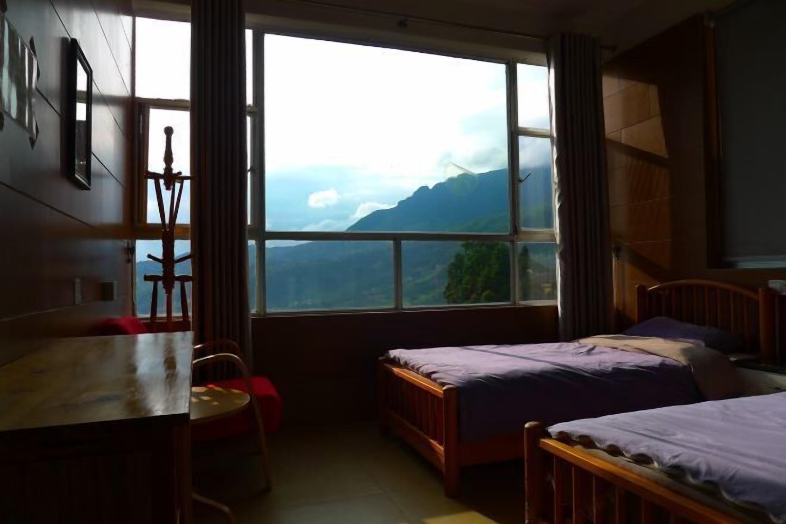 Um quarto com uma janela grande, uma cama, uma escrivaninha e uma cadeira.