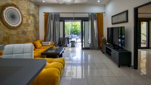 Uma sala de estar moderna com sofá, televisão e área de jantar.