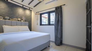 Quarto com cama, cabeceira, janela com cortinas, ar condicionado e luminária suspensa.
