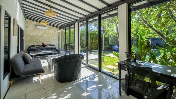 Uma sala de estar moderna e espaçosa, com sofá, cadeira de vime e mesa de jantar.