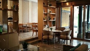 Uma sala de estar ampla com uma mesa de jantar, cadeiras e um sofá. Há estantes e uma mesa de centro.