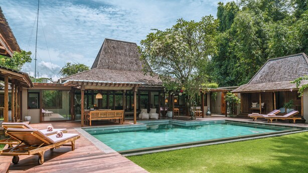Área da piscina com deck de madeira, espreguiçadeiras e um espaço de estar coberto.