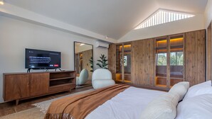 Quarto moderno com cama grande, televisão, guarda-roupa de madeira e um claraboia.