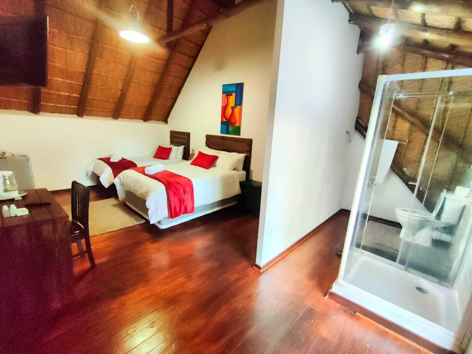 Quarto com duas camas, uma escrivaninha e área de chuveiro.