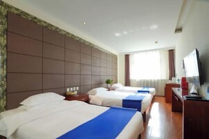 Quarto de hotel com duas camas, uma mesa, televisão e janela com cortinas.