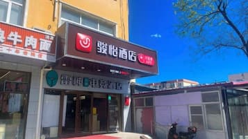 Hotel com placa vermelha e branca, uma motocicleta estacionada na frente e céu azul claro.