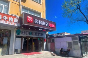 Hotel com placa vermelha e branca, uma motocicleta estacionada na frente e céu azul claro.