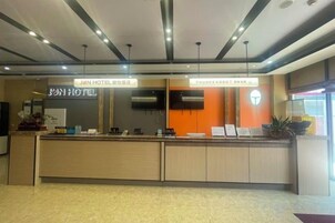 Uma área de recepção de hotel com balcão, televisão e placa com o nome do hotel.
