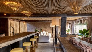 Uma área de bar moderna com banquetas de madeira, um balcão longo e um design de teto singular.