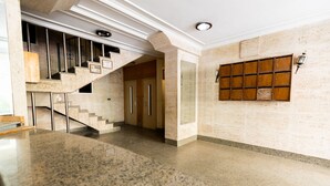 Um hall amplo com piso de mármore, escada e luminária fixada na parede.