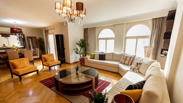 Uma sala de estar espaçosa com sofá, poltronas, mesa de centro e área de jantar com cadeiras e mesa.