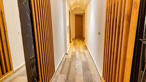 Um corredor com ripas de madeira nas paredes, piso de madeira e uma porta no final.