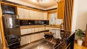 Uma cozinha moderna com bancadas de mármore preto, armários de madeira e uma geladeira de aço inoxidável.