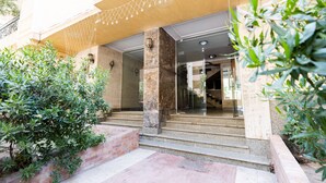 Entrada de hotel com fachada de pedra, portas de vidro e um caminho de tijolos que leva à entrada.
