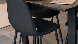 Uma sala de estar moderna com uma mesa de madeira escura, um laptop, um copo de água e um jarro de vidro.