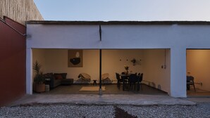 Uma casa moderna com um pátio que inclui uma mesa de jantar, cadeiras e um sofá.