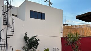 Um edifício moderno com fachada branca, escada em espiral e uma pequena janela.