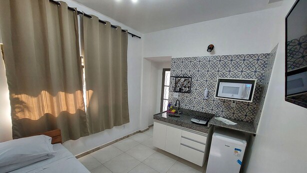 Cozinha compacta com micro-ondas, pia e armários.