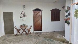 Um pátio com uma porta de madeira, uma mesa com cadeiras e plantas em vasos.