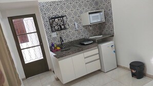 Uma cozinha compacta com micro-ondas, pia e geladeira.
