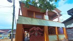 Um edifício de dois andares com entrada protegida por portão, placa visível e céu claro.