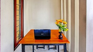 Uma mesa de madeira com um laptop e um vaso de flores.
