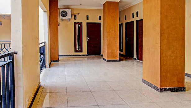 Um corredor com piso de azulejos, colunas de madeira e um ventilador de teto.