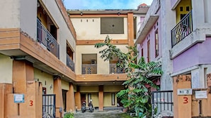 Pátio com edif ícios de dois andares, uma escadaria central e um portão com o número 3.