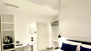 Quarto de hotel com uma cama, escrivaninha, cadeira, guarda-roupa e uma pequena cozinha.