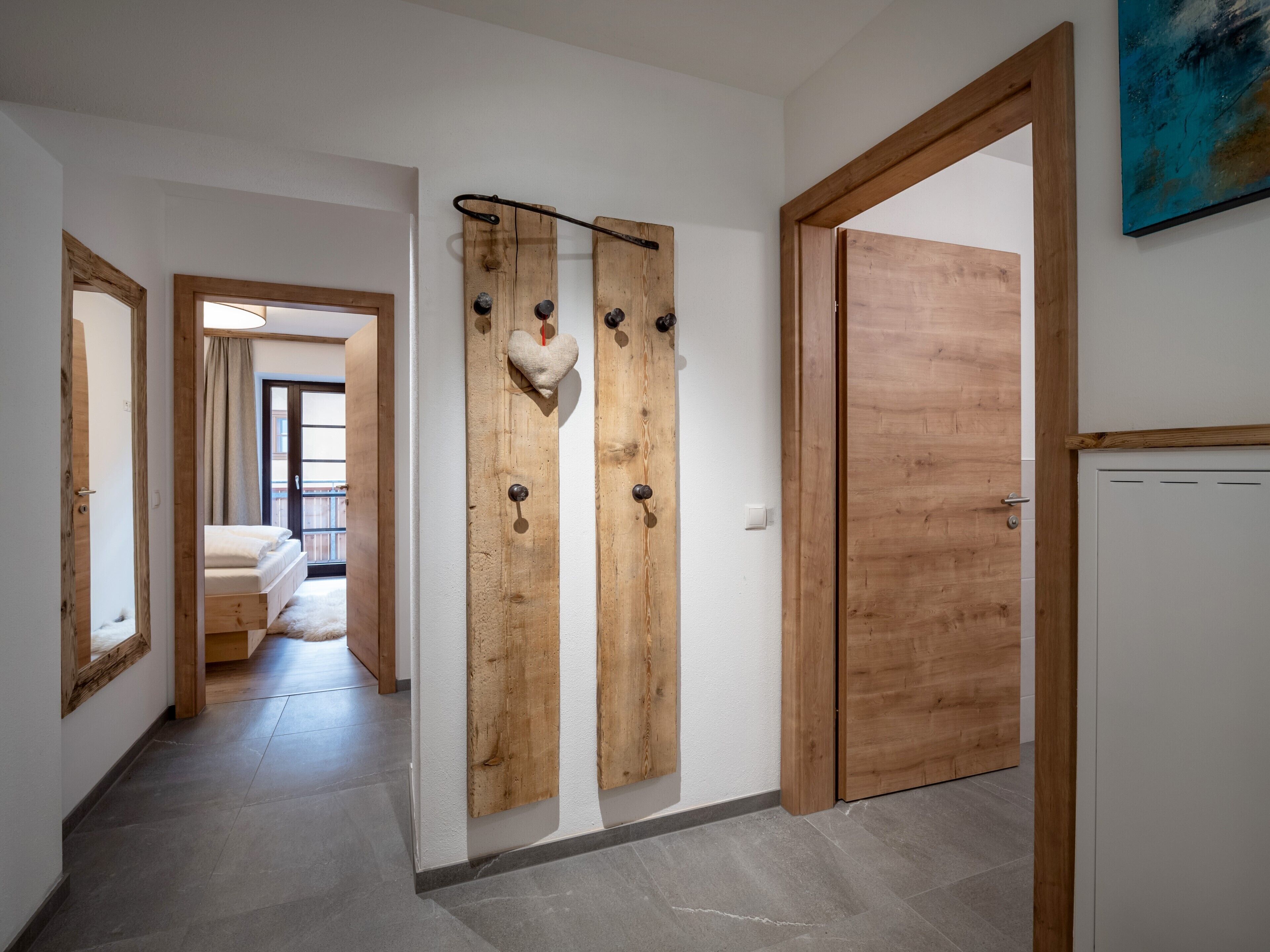 Corredor com portas de madeira, uma cama e vista para uma varanda.