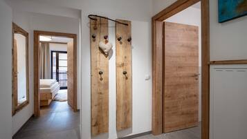Corredor com portas de madeira, uma cama e vista para uma varanda.