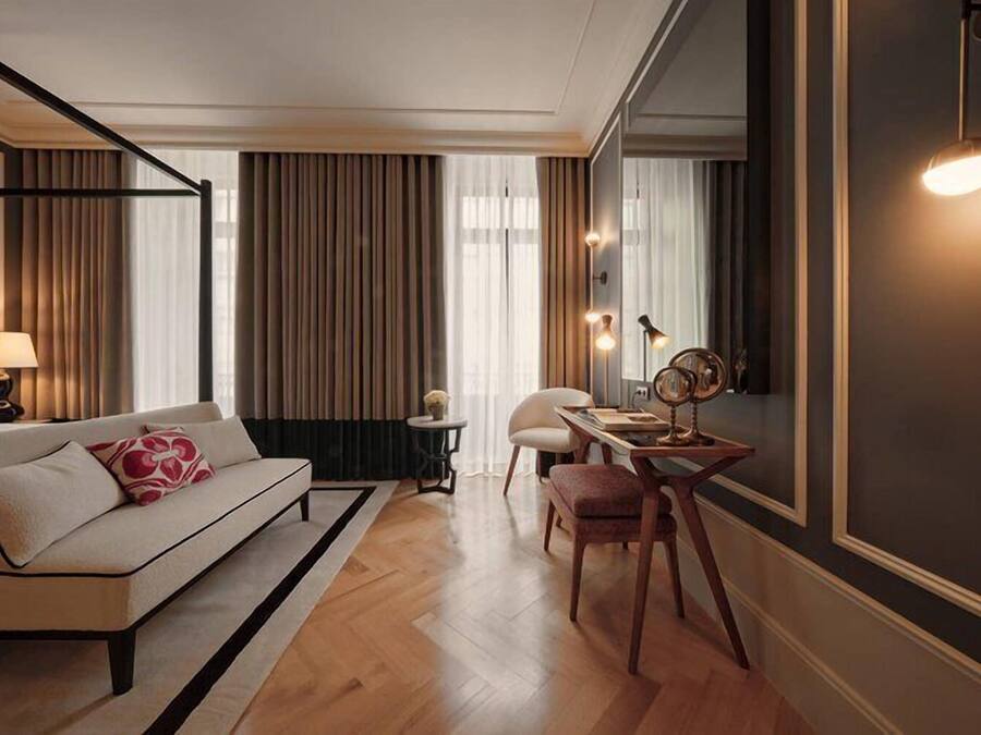 Quarto de hotel moderno com sofá, escrivaninha e cadeira.
