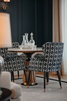 Uma área de jantar com uma mesa redonda, cadeiras estampadas e um enfeite decorativo.