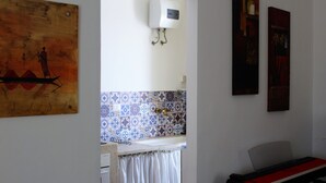 Um banheiro com revestimento de azulejos, vaso sanitário branco, porta-toalhas e um quadro na parede.