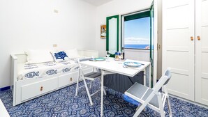 Quarto com cama, mesa, cadeira, janela e porta.