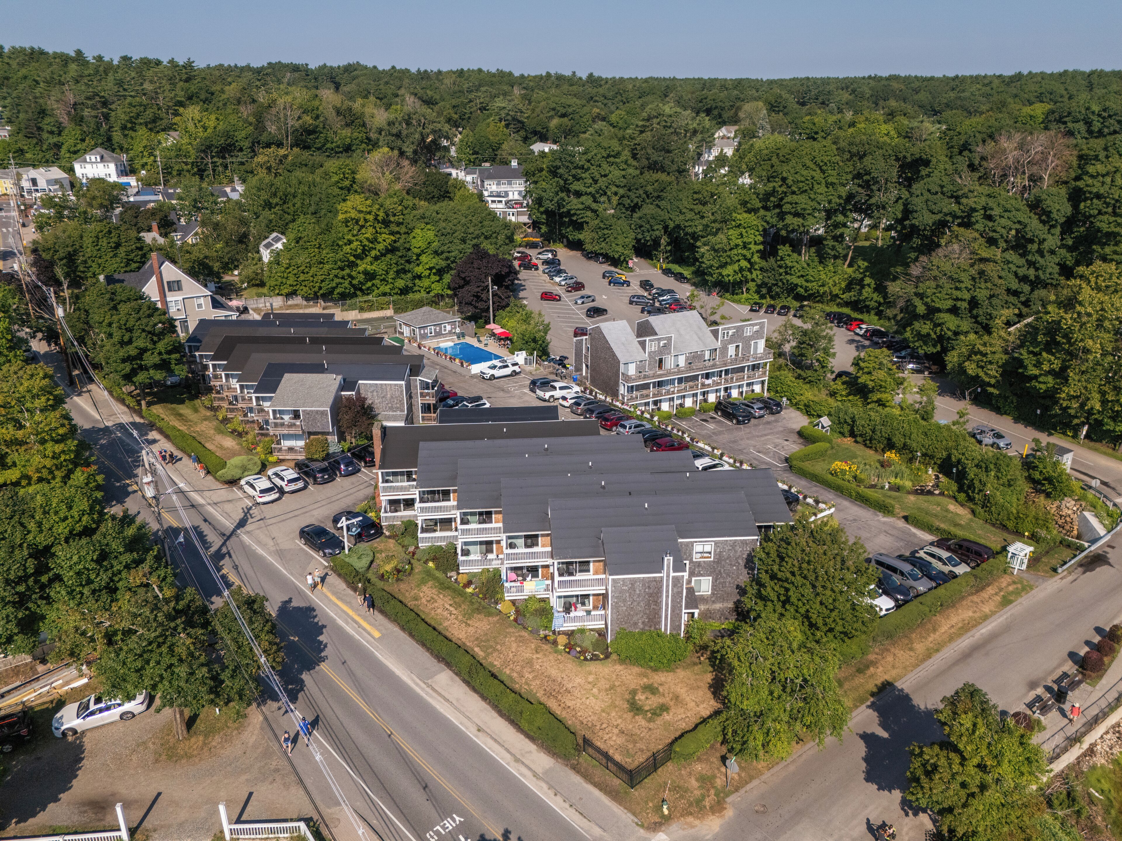 Vista aérea de um bairro residencial com várias casas de dois andares, um estacionamento e uma rua.