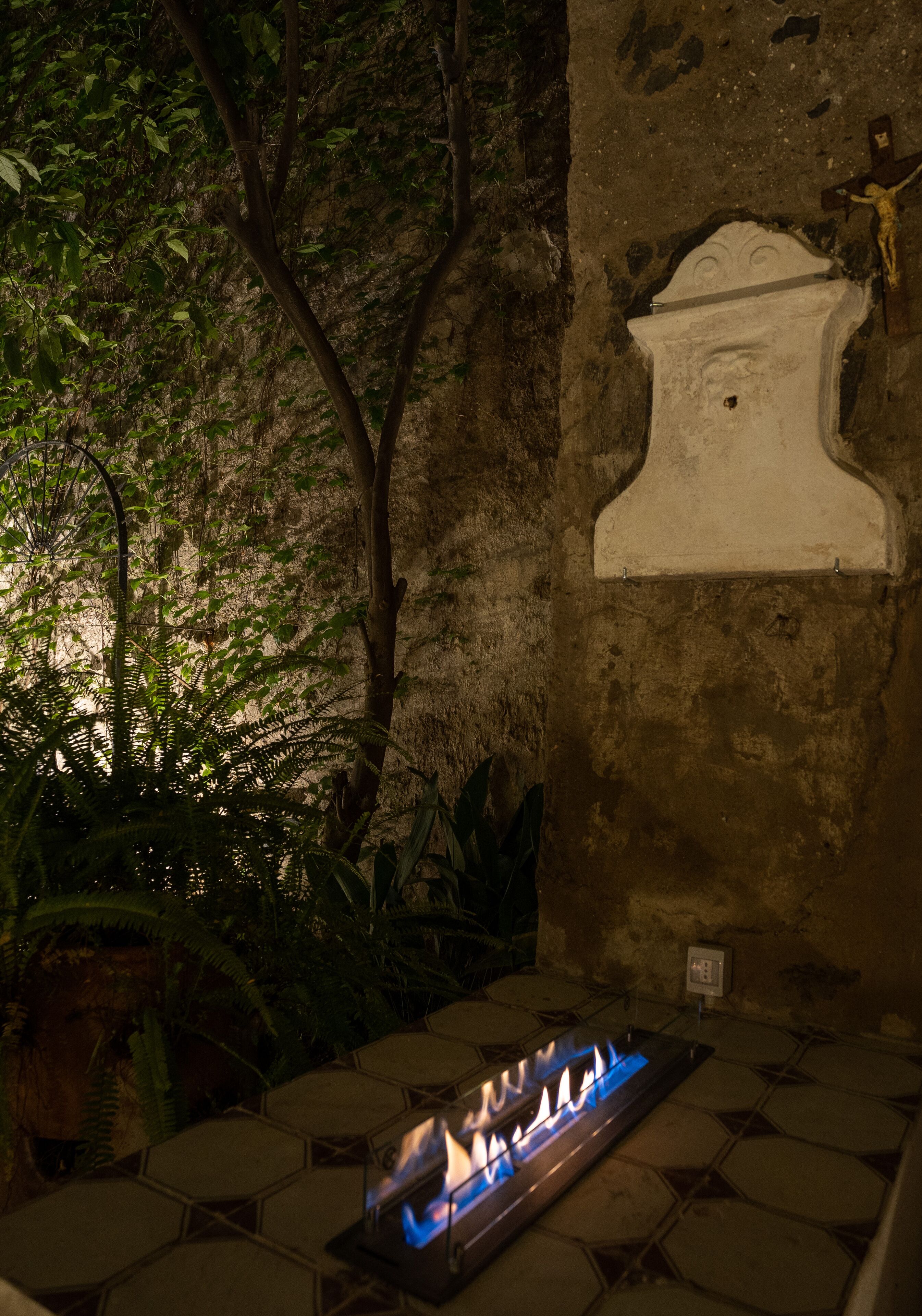 Paredes de pedra com uma cruz e chão de azulejos.