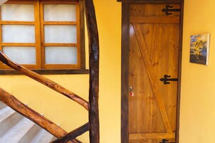 Uma porta de madeira com fechadura e puxador de metal, uma janela com vidro jateado e uma escada de madeira com corrimão.
