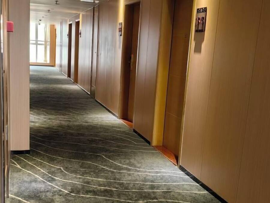 Um corredor de hotel com piso em carpete e paredes de madeira.