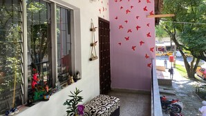 Quarto com uma janela grande, um banco e uma parede decorada com adesivos de borboletas vermelhas.