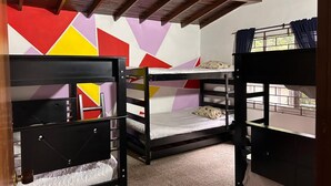 Um quarto com beliches, parede com padrão geométrico e janela com cortinas.