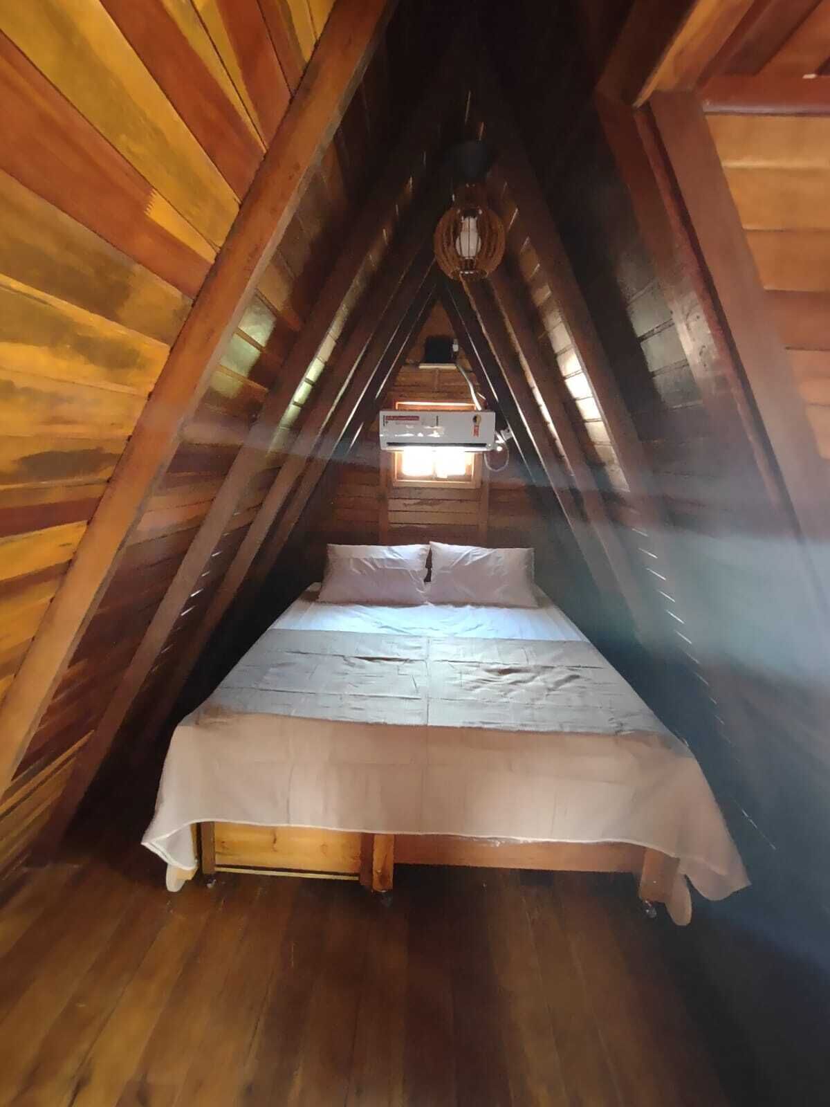 Quarto de sótão com madeira, uma cama, uma janela e um aparelho de ar condicionado.