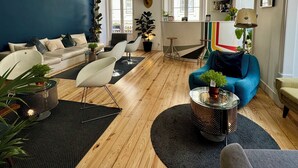 Uma sala de estar moderna com uma parede azul de destaque, um sofá, duas poltronas, uma mesa de centro e uma cabeça de veado decorativa.