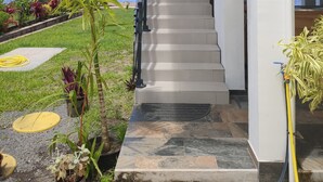 Uma escadaria moderna leva a um edifício branco, com um céu azul claro ao fundo.
