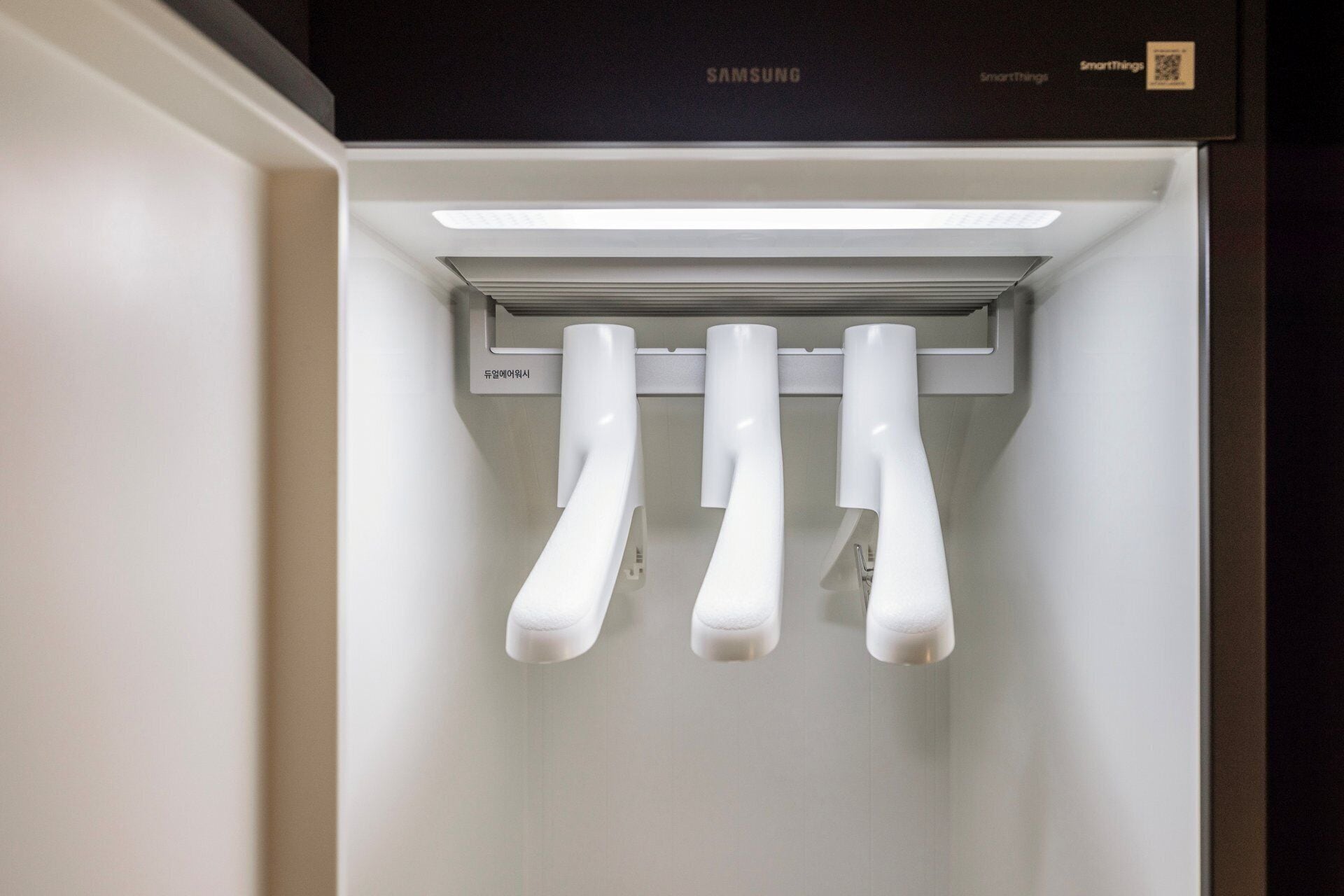 Uma geladeira Samsung com máquina de gelo integrada, dispensador de água e painel de controle com um código QR.