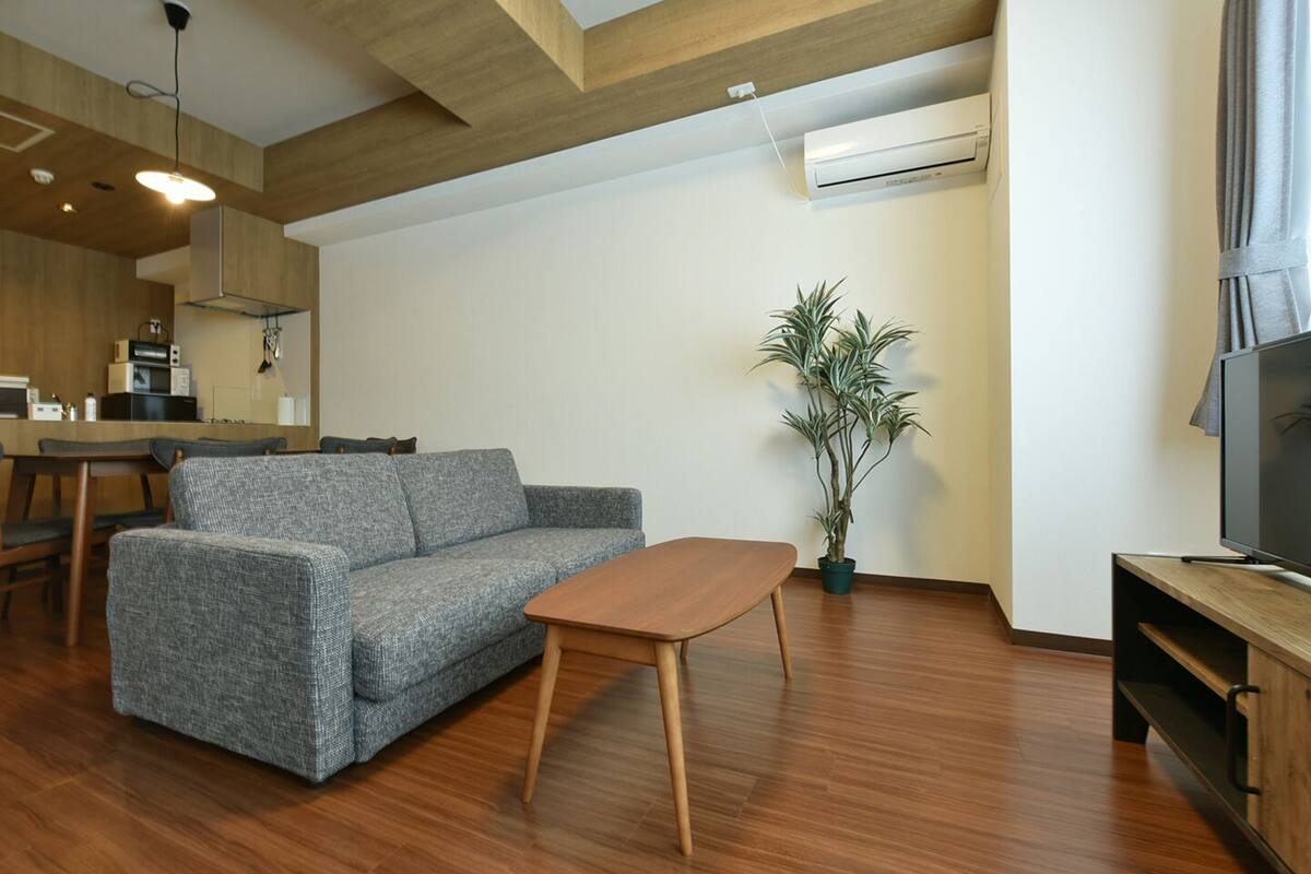 Uma sala de estar moderna com um sofá cinza, mesa de centro de madeira e um aparador para televisão.